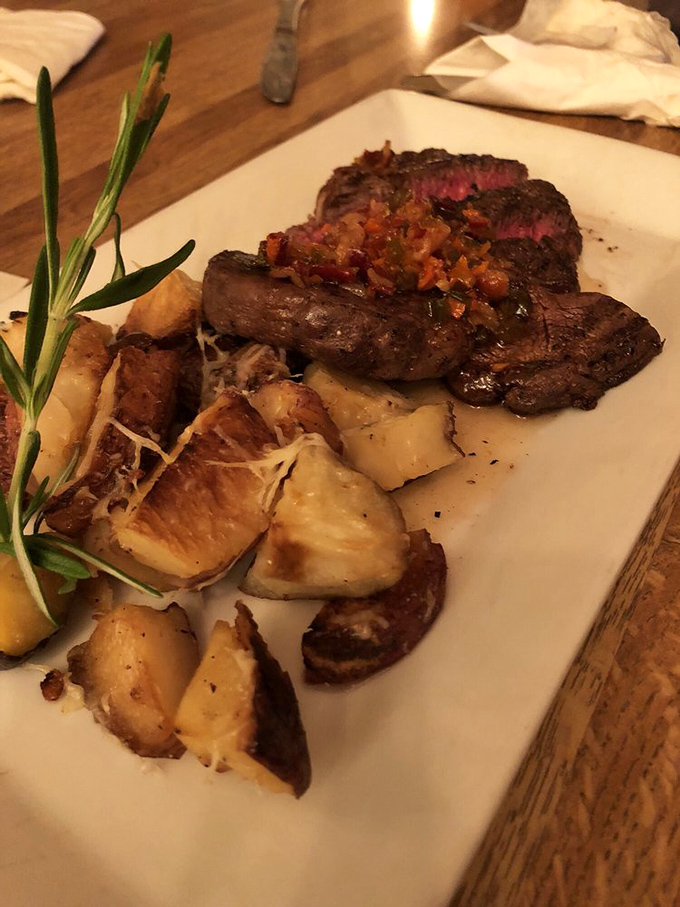 A perfectly cooked ribeye with roasted potatoes that could make a vegetarian question their life choices. The rosemary sprig isn't just garnish—it's an aromatic exclamation point.