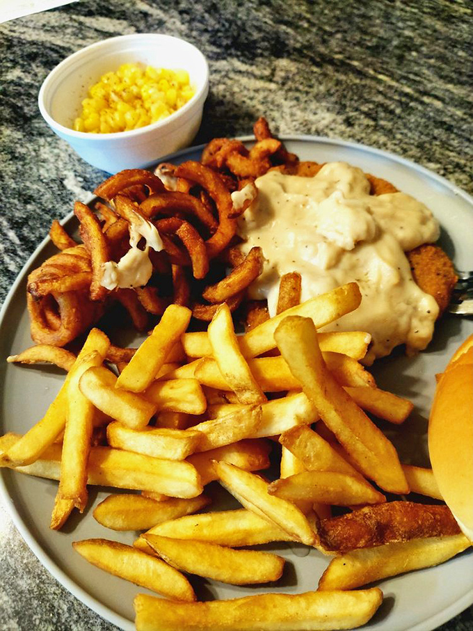 Country fried goodness smothered in creamy gravy with golden fries and onion rings standing by. This plate doesn't just feed you &ndash; it hugs you from the inside.
