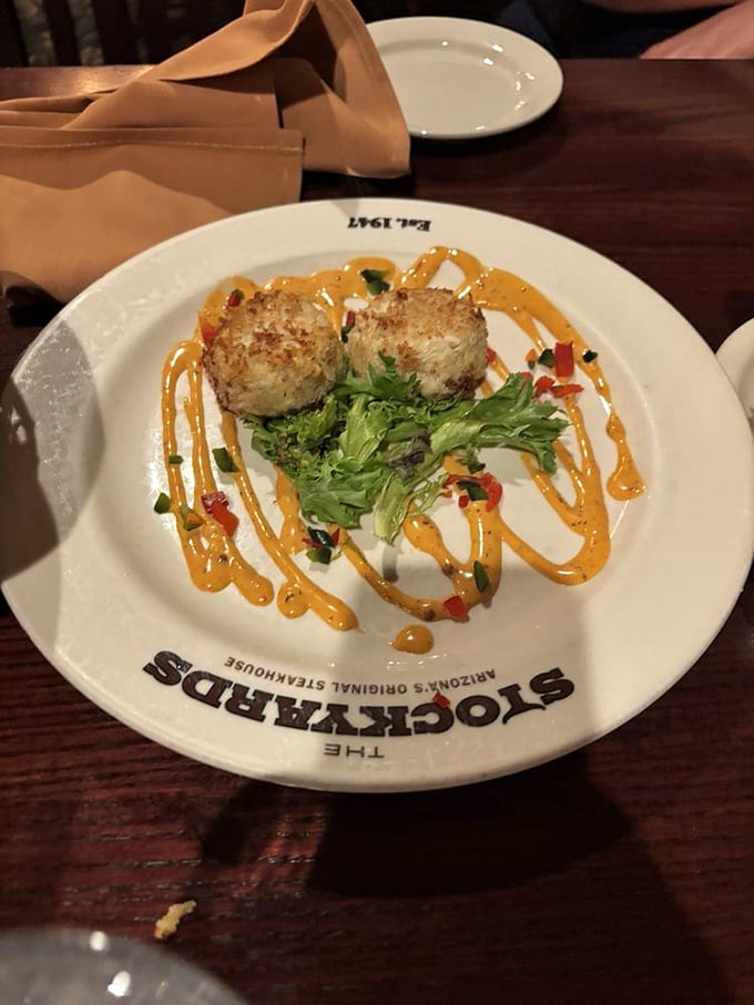 These golden crab cakes aren't just appetizers &ndash; they're the opening act to a magnificent meal, perched atop artistic swirls of sauce like culinary royalty.