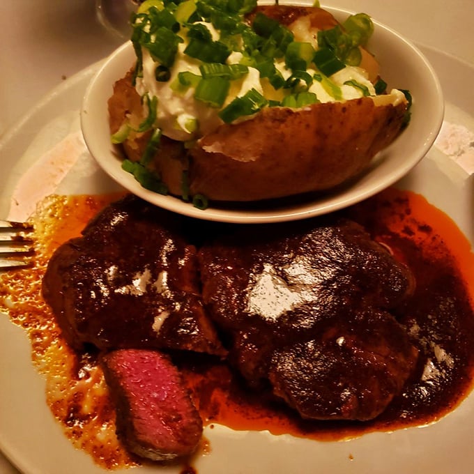Filet mignon bathed in rich sauce with a baked potato standing by. This plate doesn't need Instagram filters&mdash;it's naturally photogenic.
