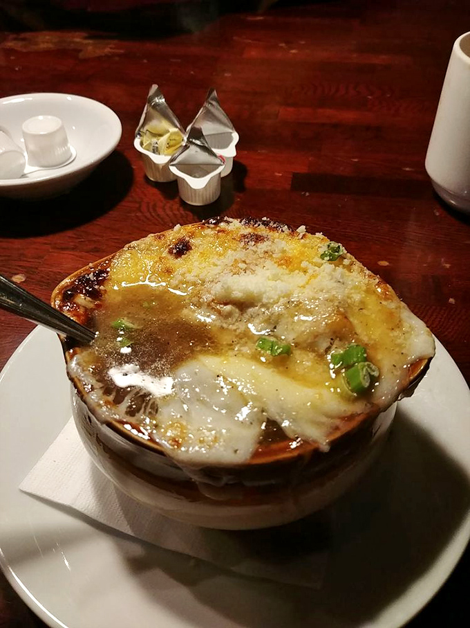 Bubbling cheese creates the perfect golden canopy over this French onion soup. Spoon-breaking crust that's worth every calorie.