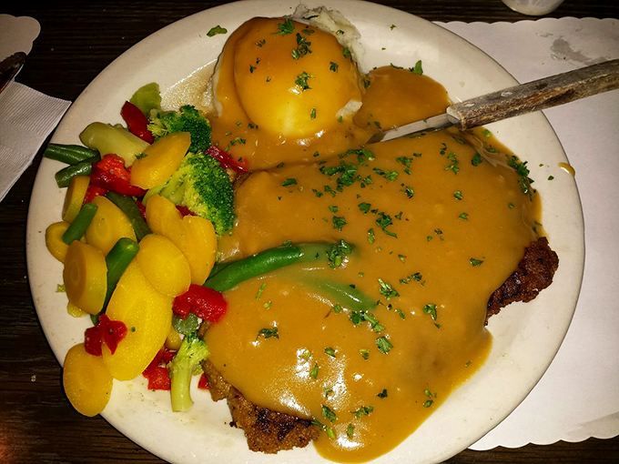 Country fried steak swimming in gravy&mdash;where comfort food meets California fresh. Those colorful vegetables aren't just for show; they're delicious co-conspirators.