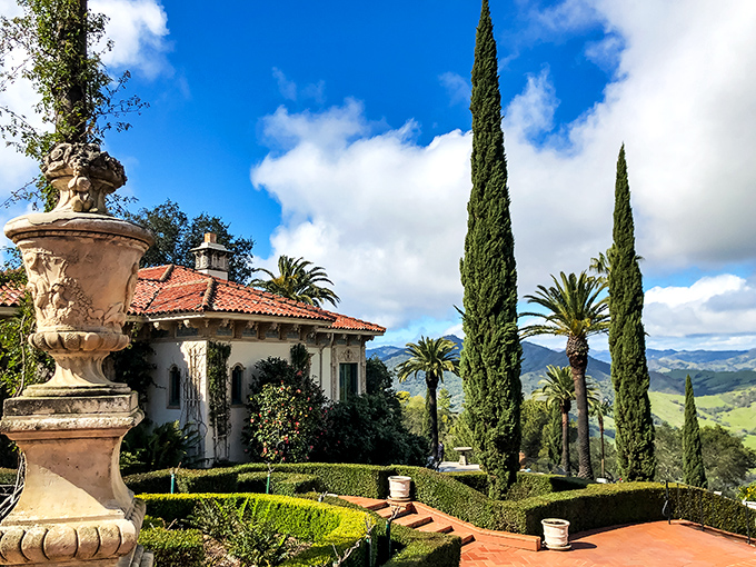 Mediterranean cypress trees stand like exclamation points against the California sky, framing guest houses that make five-star hotels look like roadside motels.