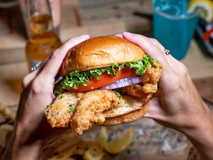 Hands holding happiness: a perfectly fried fish sandwich stacked with fresh veggies. Some people take beach photos; I take sandwich portraits.