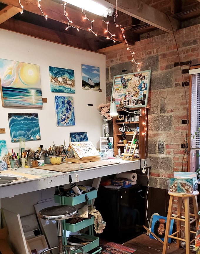 An artist's corner where creativity flows &ndash; ocean-inspired paintings and well-worn brushes hint at the artistic community thriving within these brick walls. 