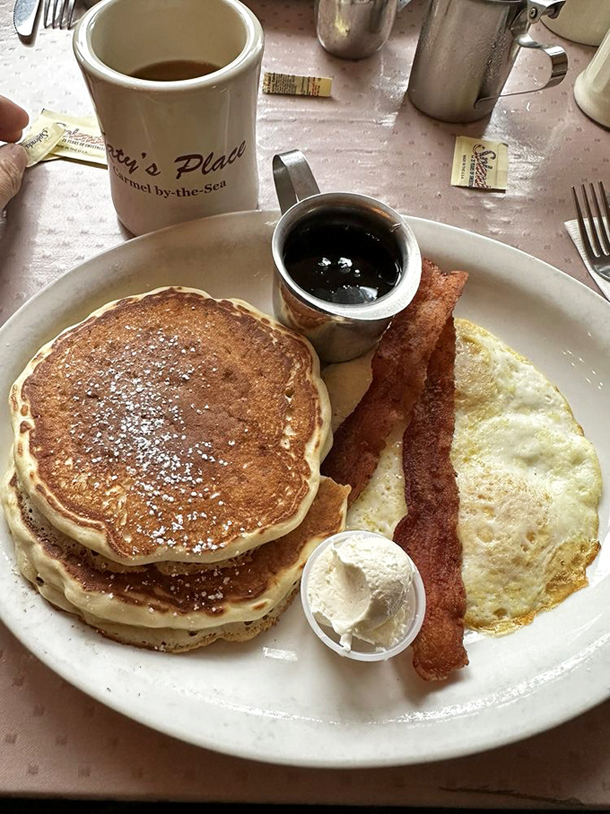 The breakfast trinity: golden pancakes, crispy bacon, and a sunny-side-up egg &ndash; proof that sometimes the classics are classics for good reason.