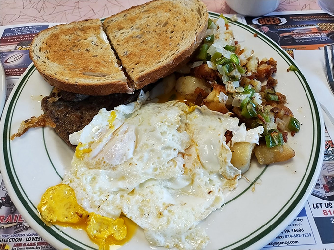 Breakfast alchemy: eggs, perfectly seasoned home fries with peppers and onions, and toast that knows its supporting role in this morning symphony.