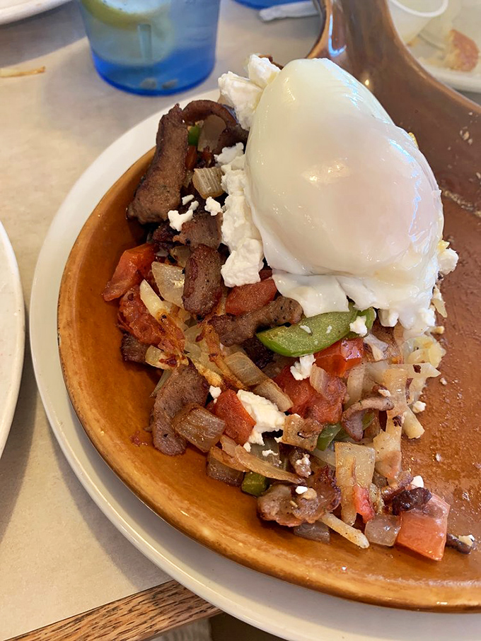 A skillet that tells a story of vegetables, meat, and cheese coming together for a morning summit, crowned with an egg diplomat.
