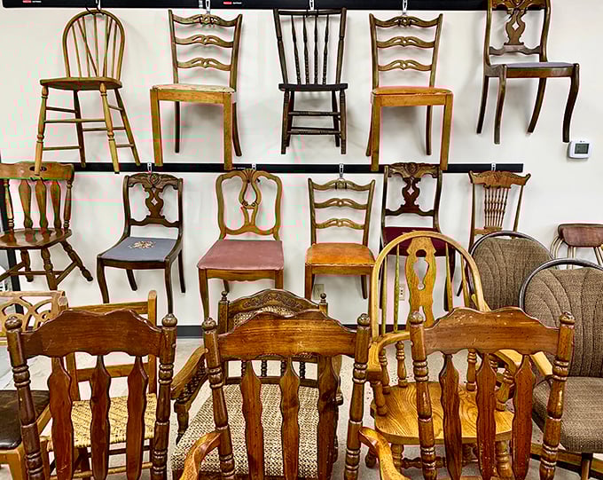 The wall of chairs resembles a wooden family reunion. Each one has a story, a distinct personality, and probably knows what your posture needs.