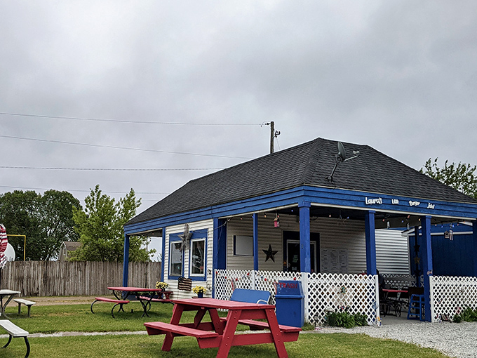 Red picnic tables and white lattice fencing create the perfect backyard cookout vibe. Laura's blue building is a roadside smile.
