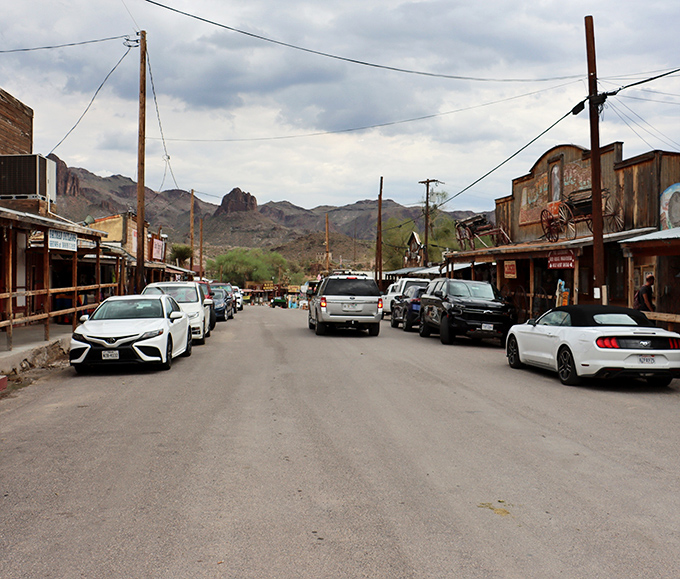 Rustic wooden buildings line Oatman's main drag, where modern cars park alongside structures that witnessed the gold rush era.