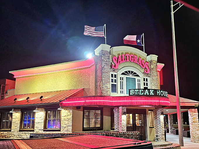 Night falls on Saltgrass Steakhouse, where the red glow promises a warm welcome and steaks that taste like Texas itself.