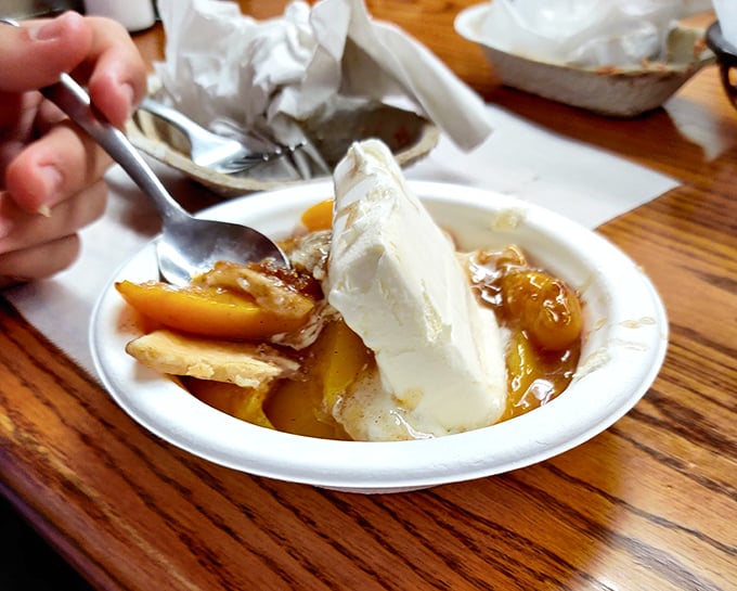 When barbecue meets dessert: warm peach cobbler topped with vanilla ice cream creates the kind of sweet finale that makes you forget your belt is already tight.