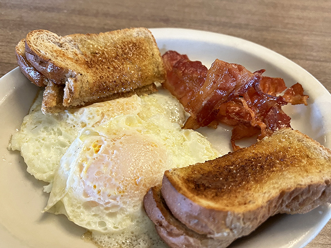 The breakfast that launched a thousand productive mornings: perfectly sunny-side-up eggs, crispy bacon, and toast ready for butter's warm embrace.