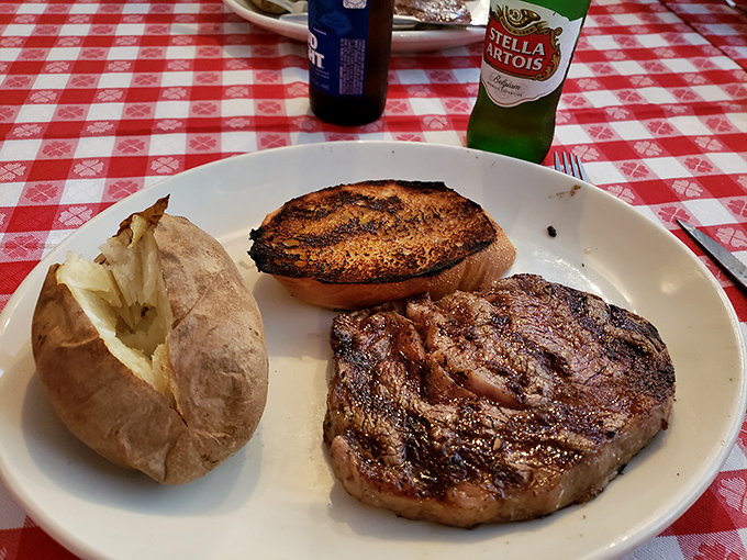 Beer bottles stand at attention beside a steak and potato—the holy trinity of American dining, served on classic diner plates.