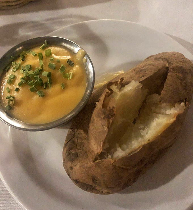 A baked potato split open like nature's perfect vessel for that river of cheese sauce. Comfort food engineering at its finest.