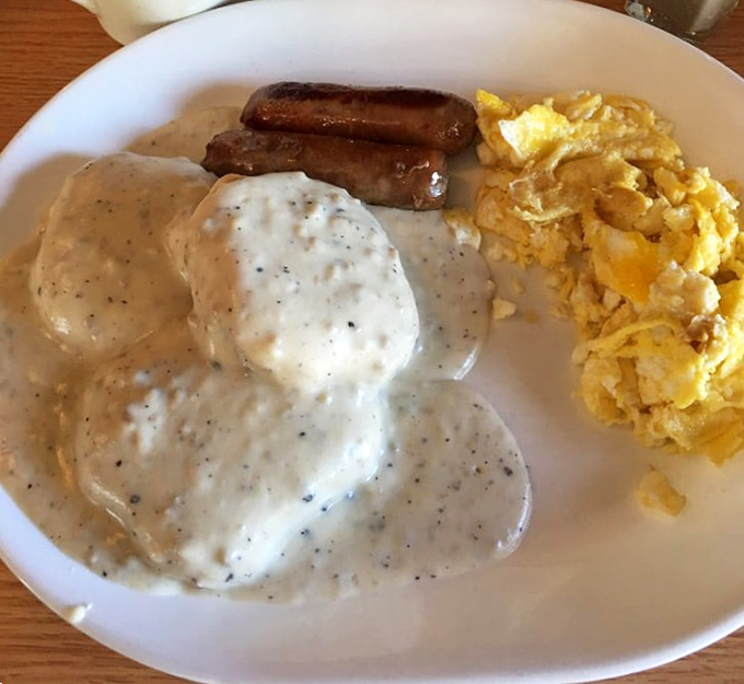 Country gravy blankets biscuits like a warm Southern hug, with scrambled eggs and sausage completing this comfort food trifecta.