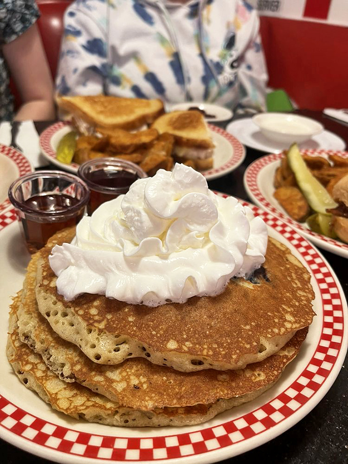 These pancakes aren't just breakfast, they're an event. That mountain of whipped cream is basically a snow-capped peak of morning delight.