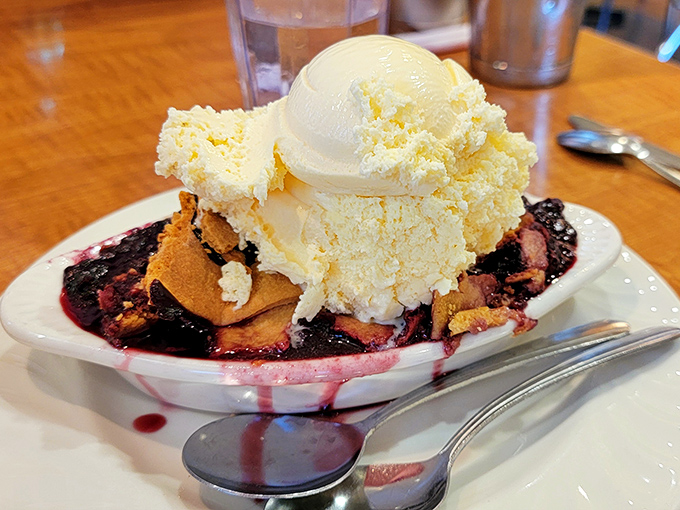 The boysenberry cobbler arrives like a purple dream, crowned with vanilla ice cream that's already surrendering to the warm fruit below.