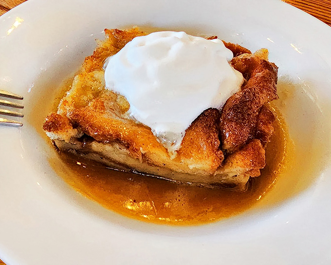 Bread pudding that makes you question why anyone bothers with fancy desserts when this sweet, custardy perfection exists, especially with that glorious sauce pooling around it.