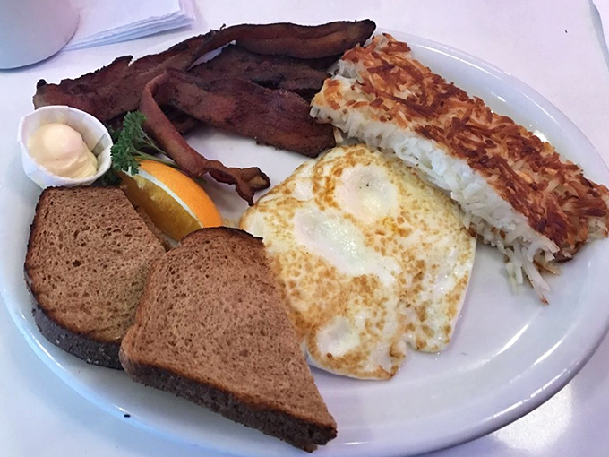 The breakfast trinity: perfectly cooked eggs, crispy hash browns, and bacon that snaps like nature intended. Add toast for the grand slam of morning satisfaction.