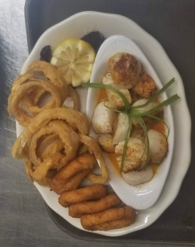 A seafood trinity&mdash;crispy onion rings, perfectly fried shrimp, and scallops seasoned with care&mdash;presented on a plate that's about to make someone very happy.
