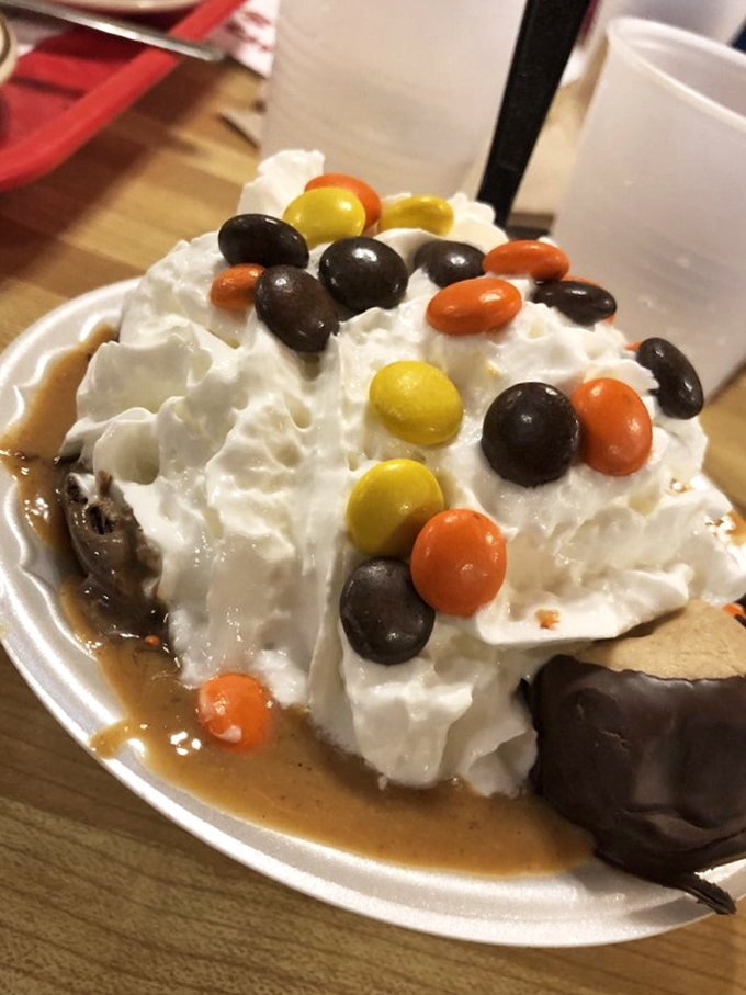 A mountain of vanilla ice cream drowning happily in caramel sauce and candy—proof that sometimes more is exactly the right amount.