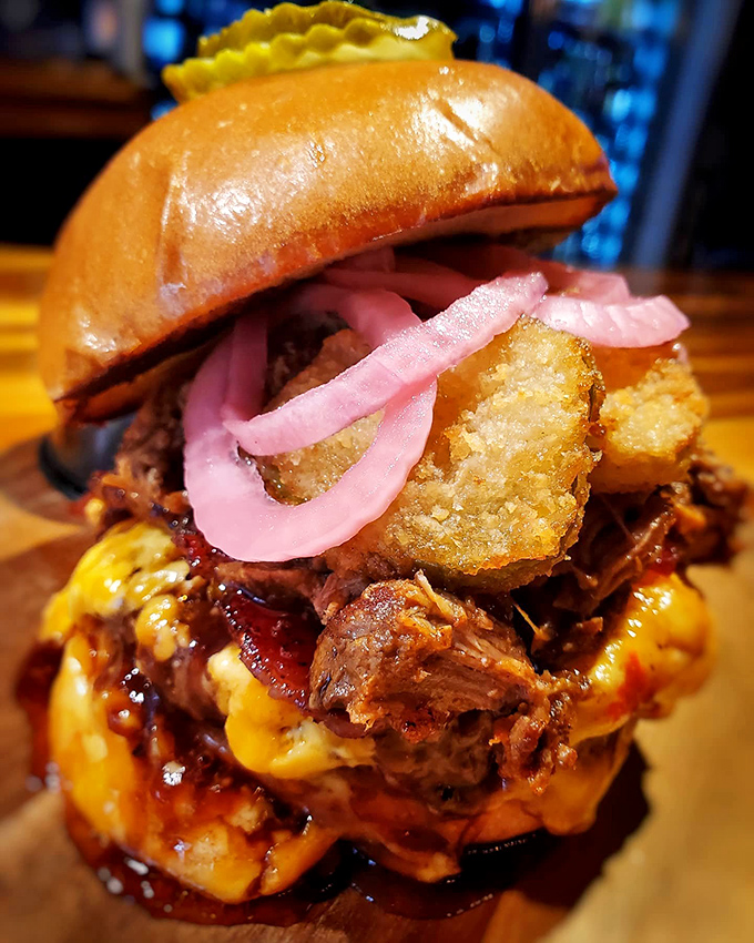 This isn't just a burger; it's a towering achievement of culinary engineering with pickled onions and tater tots that would make architects jealous.