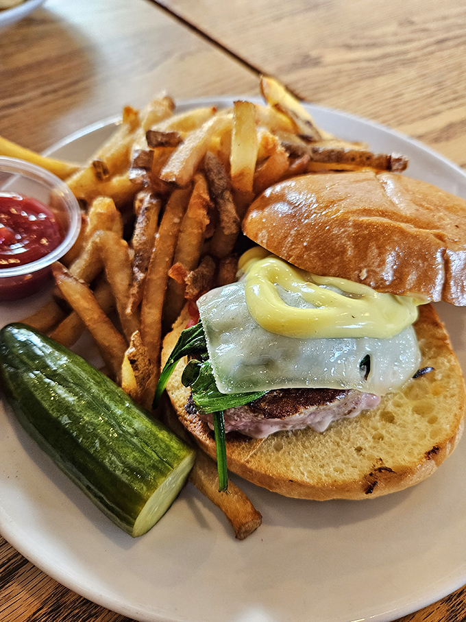 A burger that demands to be photographed before eaten&mdash;crispy fries, house-made pickle, and a bun that somehow manages to contain all that deliciousness.