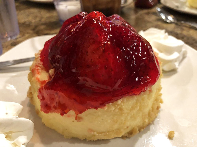 Cheesecake wearing its strawberry topping like a jaunty beret. Not just dessert &ndash; it's a fashion statement with a graham cracker foundation.