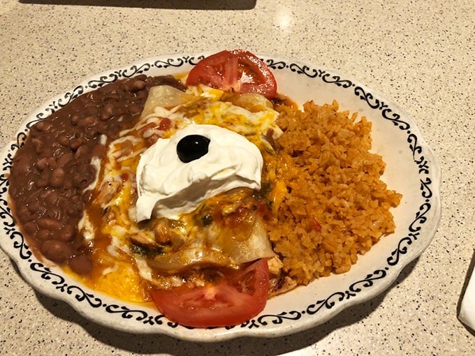 A fiesta on a plate: enchiladas smothered in sauce, with rice and beans playing the perfect supporting roles.