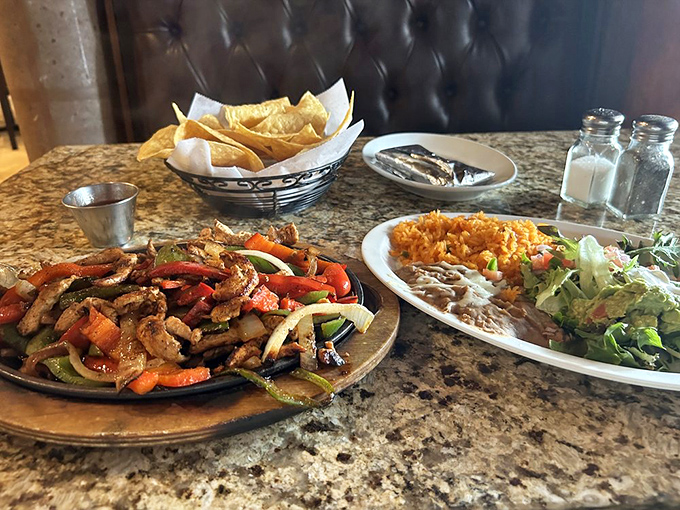 Sizzling fajitas that announce their arrival before you see them. That wooden platter carries enough seasoned protein and veggies to feed a small mariachi band.