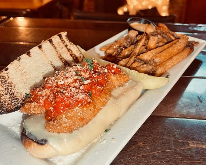 A sandwich that deserves its own ZIP code &ndash; crispy chicken parmesan nestled in melted cheese with perfectly golden fries standing guard nearby.