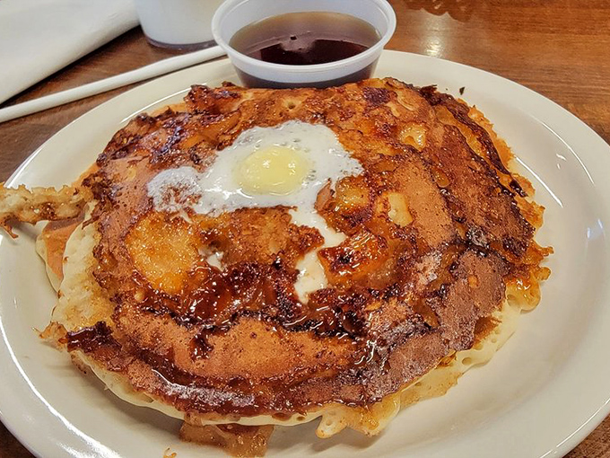 This cinnamon swirl pancake with its sunny-side-up crown isn't just breakfast—it's performance art that happens to taste like childhood memories dipped in maple syrup.