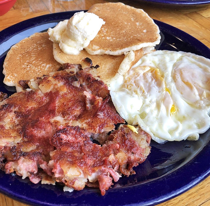 The breakfast trifecta: crispy hash browns, perfectly cooked eggs, and pancakes with a dollop of butter. The holy trinity of morning satisfaction.