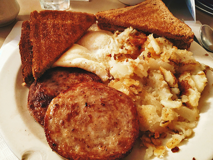 The holy trinity of diner breakfast: perfectly crisped corned beef hash, eggs with runny yolks, and home fries that somehow achieve both crispy and tender.