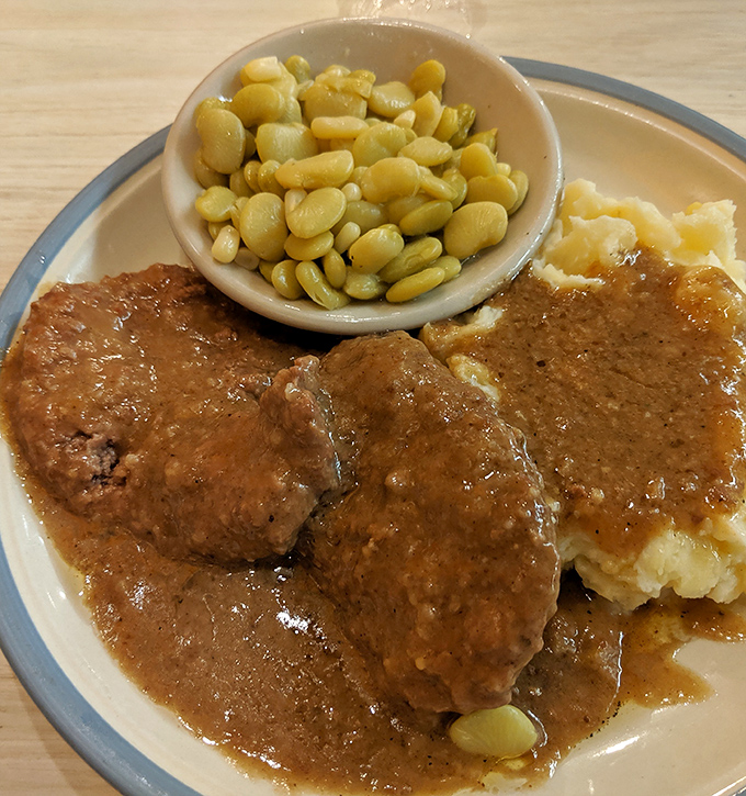 Country-style steak swimming in gravy that could make a vegetarian reconsider life choices, with buttery lima beans standing guard.