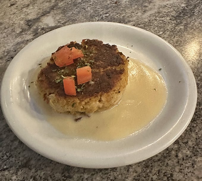 This crab cake isn't hiding behind fillers&mdash;it's proudly showcasing its crabby credentials with a golden crust and delicate sauce.