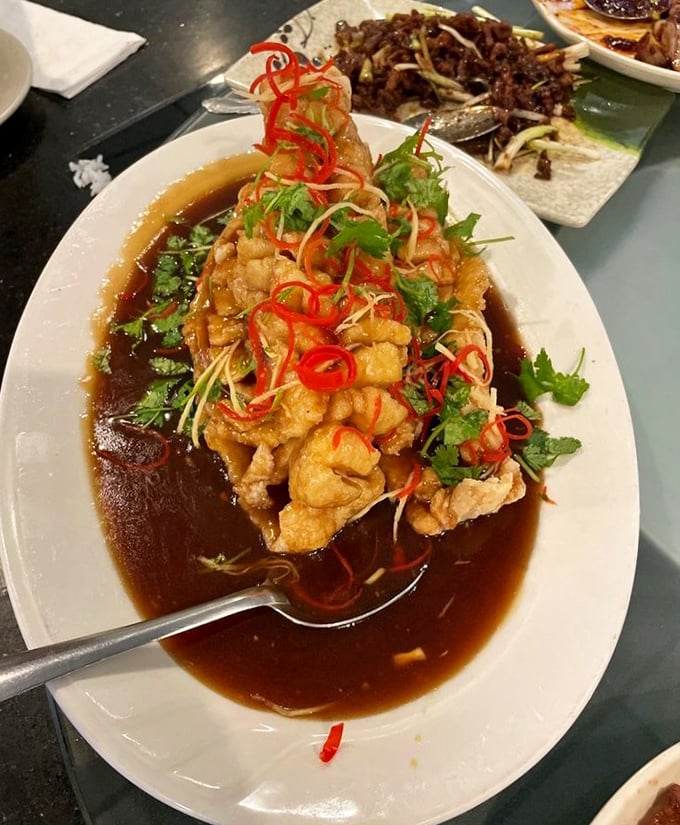 The crispy flounder arrives like a culinary showstopper, bathed in savory sauce and topped with vibrant garnishes that make your taste buds stand at attention.