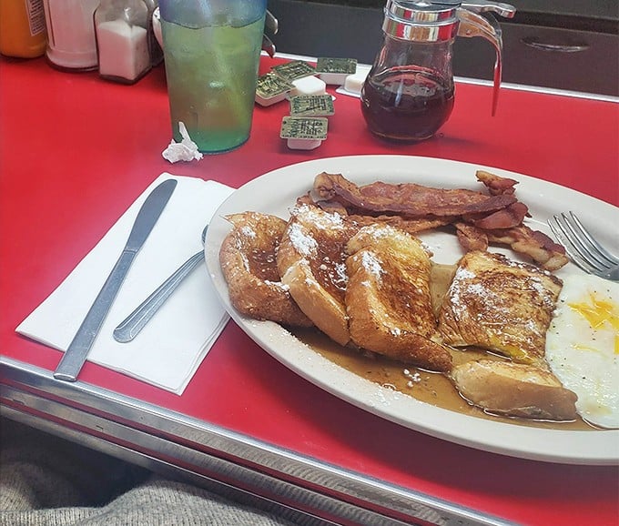 The holy trinity of breakfast: French toast wearing a coat of powdered sugar, eggs cooked just right, and bacon that's achieved that perfect crisp-chewy balance.