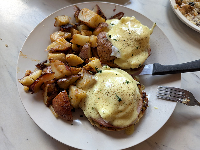 Eggs Benedict that would make a brunch enthusiast weep tears of hollandaise joy, paired with home fries that clearly grew up in a loving potato family.