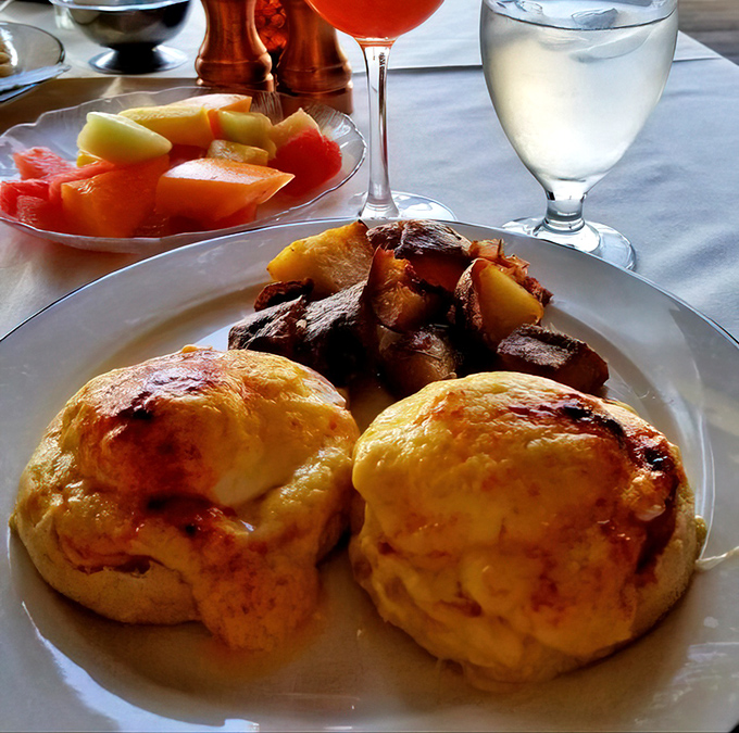 Classic eggs Benedict paired with crispy roasted potatoes showcases why people drive hours for this legendary brunch experience.