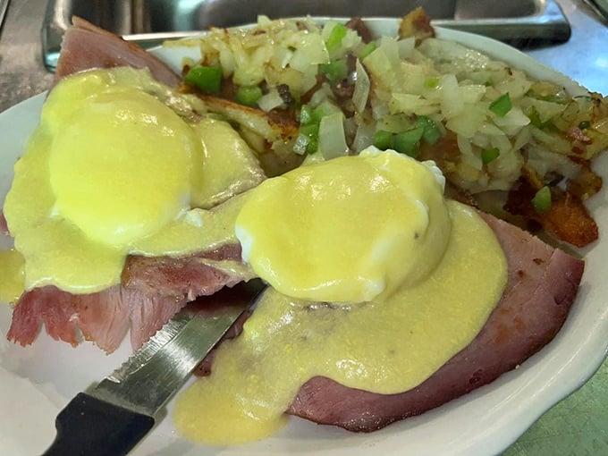 Eggs Benedict with a side of those famous home fries—hollandaise sauce cascading like a yellow waterfall of buttery goodness.