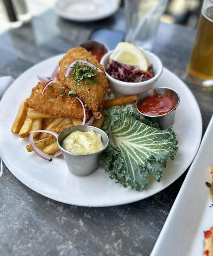 Fish and chips that would make a British pub jealous, with a cabbage leaf standing guard like a crispy sentinel of freshness.