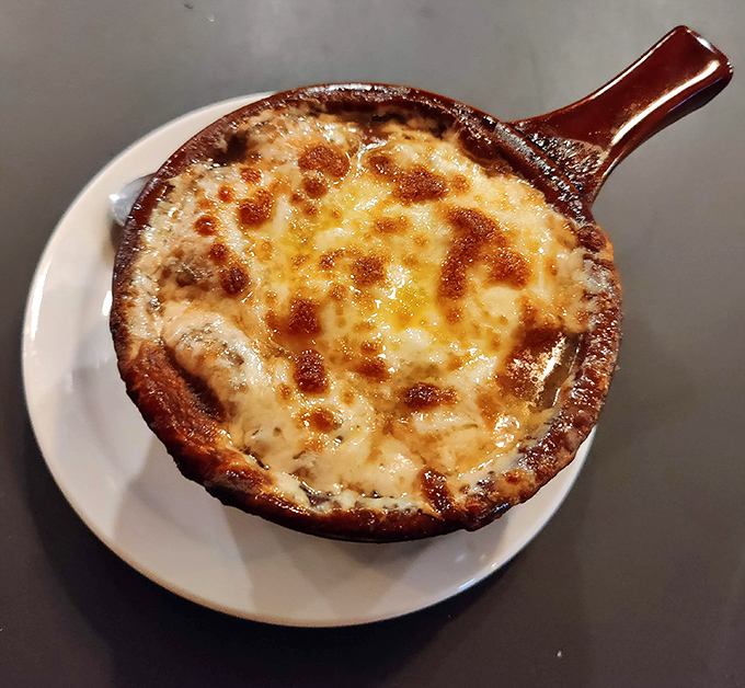 French onion soup that's achieving the perfect cheese-pull moment. That golden, bubbling crust hides a rich broth below that took someone serious hours to develop.