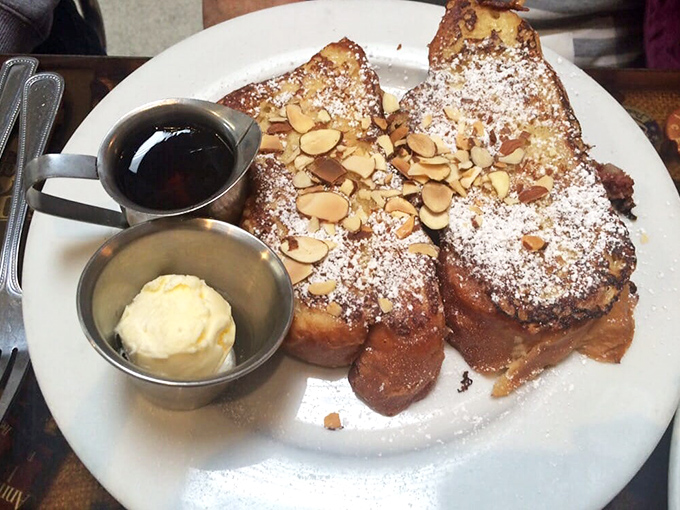 Challah French toast that's dressed for success with powdered sugar, toasted almonds, and enough maple syrup to make Canada nervous.