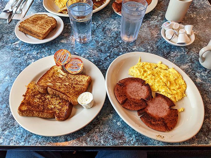 The breakfast classic duo&mdash;golden-brown French toast meeting perfectly scrambled eggs and sausage patties on their daily pilgrimage to breakfast perfection.