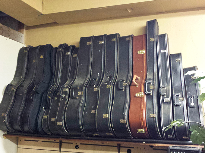 Guitar cases lined up like soldiers, each potentially hiding a six-string story of campfire songs or garage band dreams.