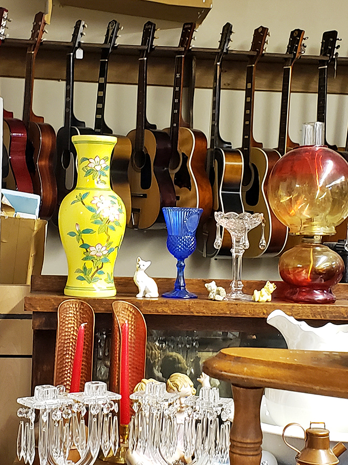 A choir of silent guitars waits for new hands, while colorful glassware and figurines create an eclectic symphony of vintage treasures below.