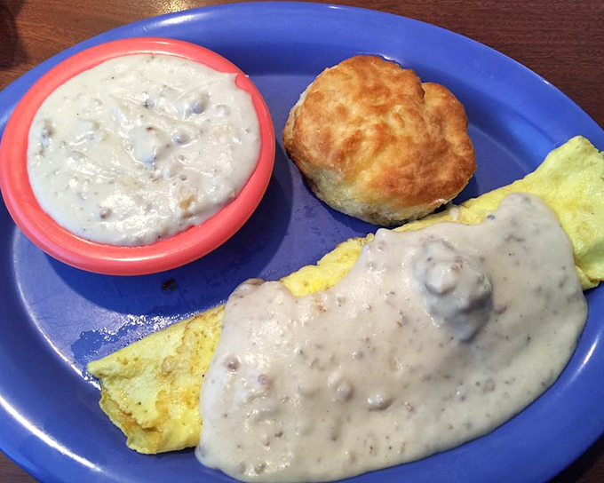 Breakfast perfection: a fluffy omelet smothered in sausage gravy with a biscuit standing by. The kind of plate that makes you want to hug the cook.